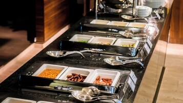 Buffet com diversos alimentos e utensílios de servir.