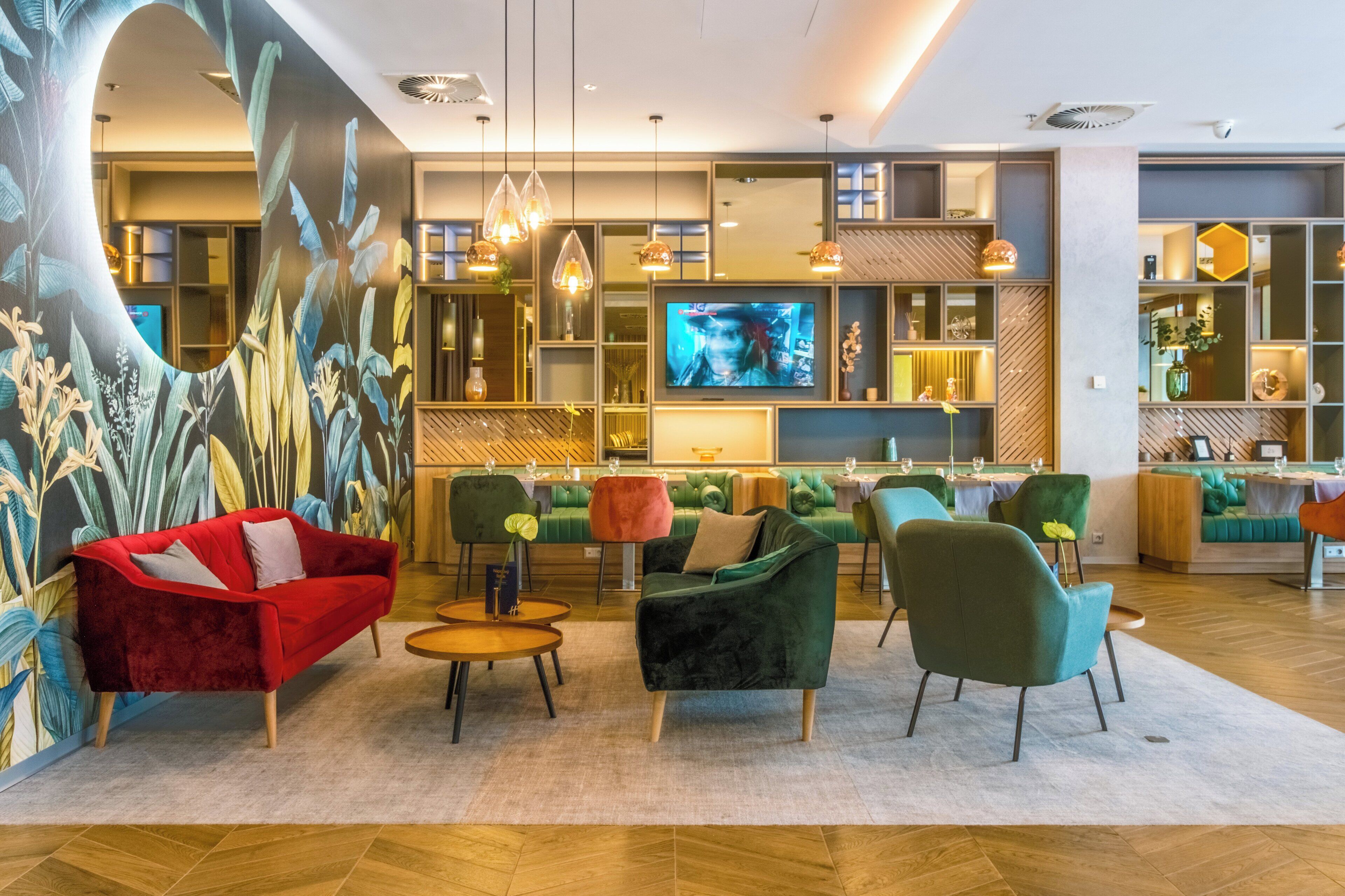 Um saguão de hotel moderno com uma TV grande, assentos confortáveis e um mural decorativo.