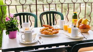 Mesa de café da manhã com croissants, frutas, suco e uma garrafa de suco de laranja.