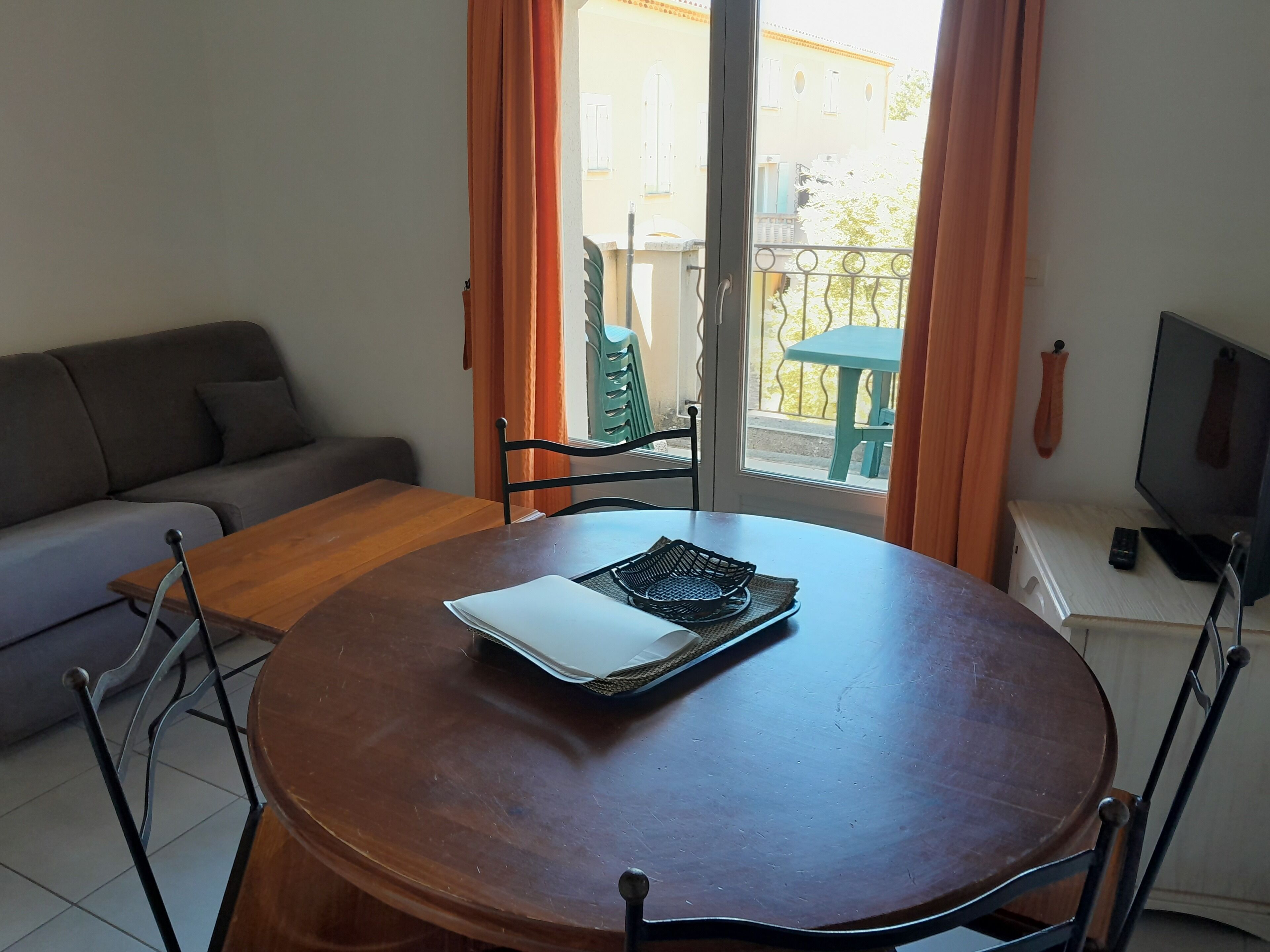 Quarto com uma mesa de madeira, um sofá e uma televisão.