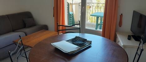 Quarto com uma mesa de madeira, um sofá e uma televisão.