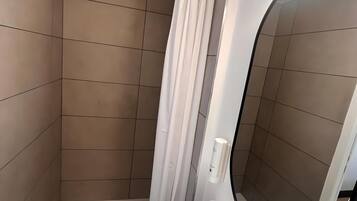 Uma casa de banho moderna com chuveiro, pia com espelho e porta-toalhas.