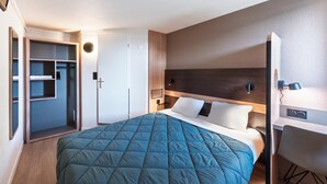 Quarto de hotel moderno com uma cama grande, uma escrivaninha e um guarda-roupa.