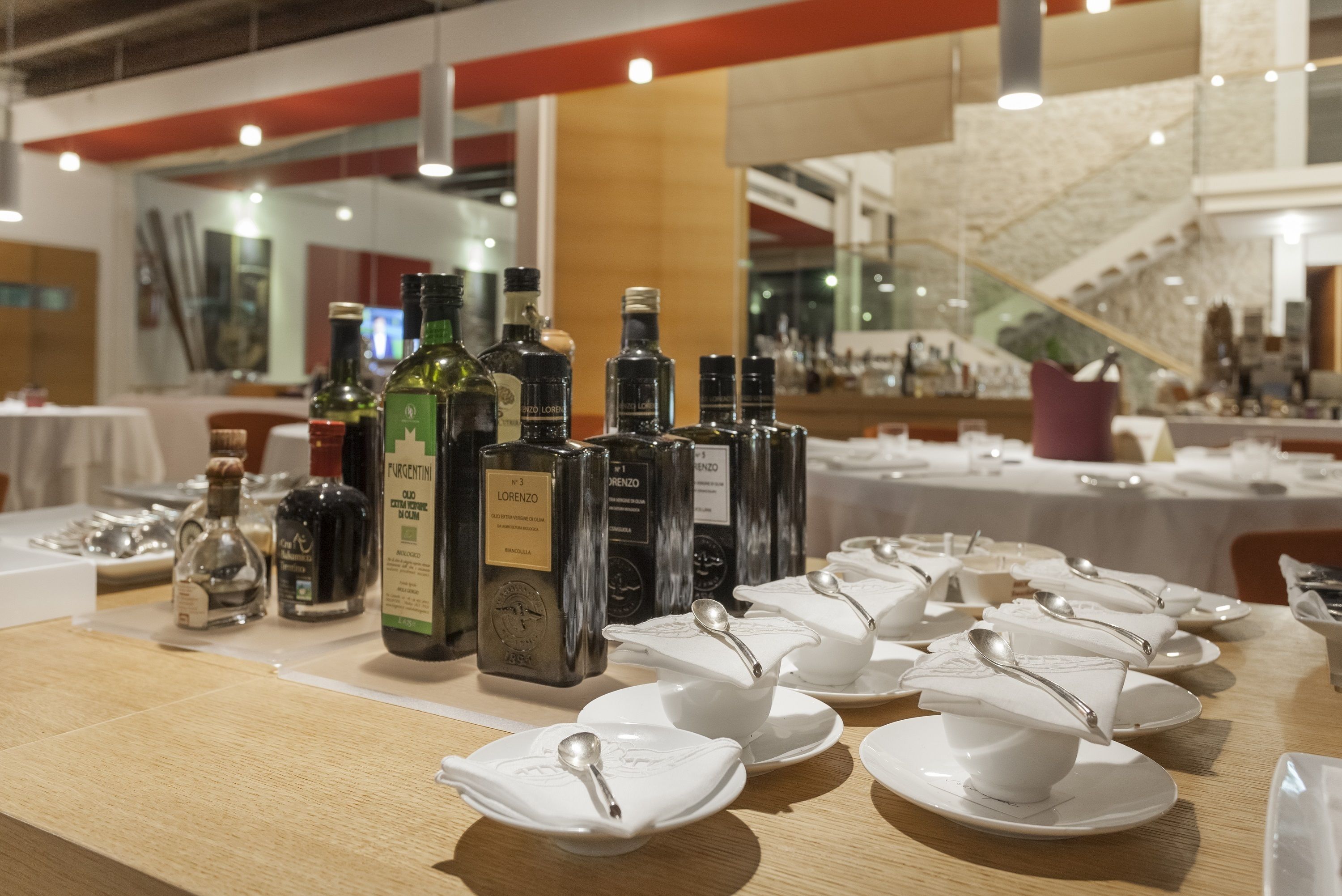 Uma mesa com várias garrafas e xícaras de chá brancas com colheres.