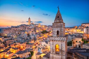 Uma cidade histórica com uma torre de igreja imponente e outra igreja menor ao fundo.