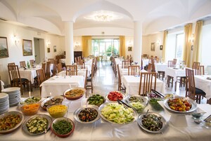 Um salão de refeições amplo, com várias mesas dispostas para um buffet, apresentando uma variedade de pratos.