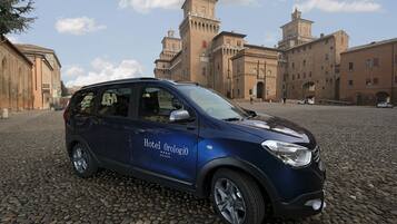 Um SUV azul estacionado em uma rua de paralelepípedos, com edifícios históricos ao fundo.