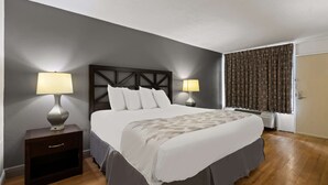 Uma cama bem arrumada com cabeceira, duas luminárias de cabeceira, mesa de cabeceira e janela com cortinas.
