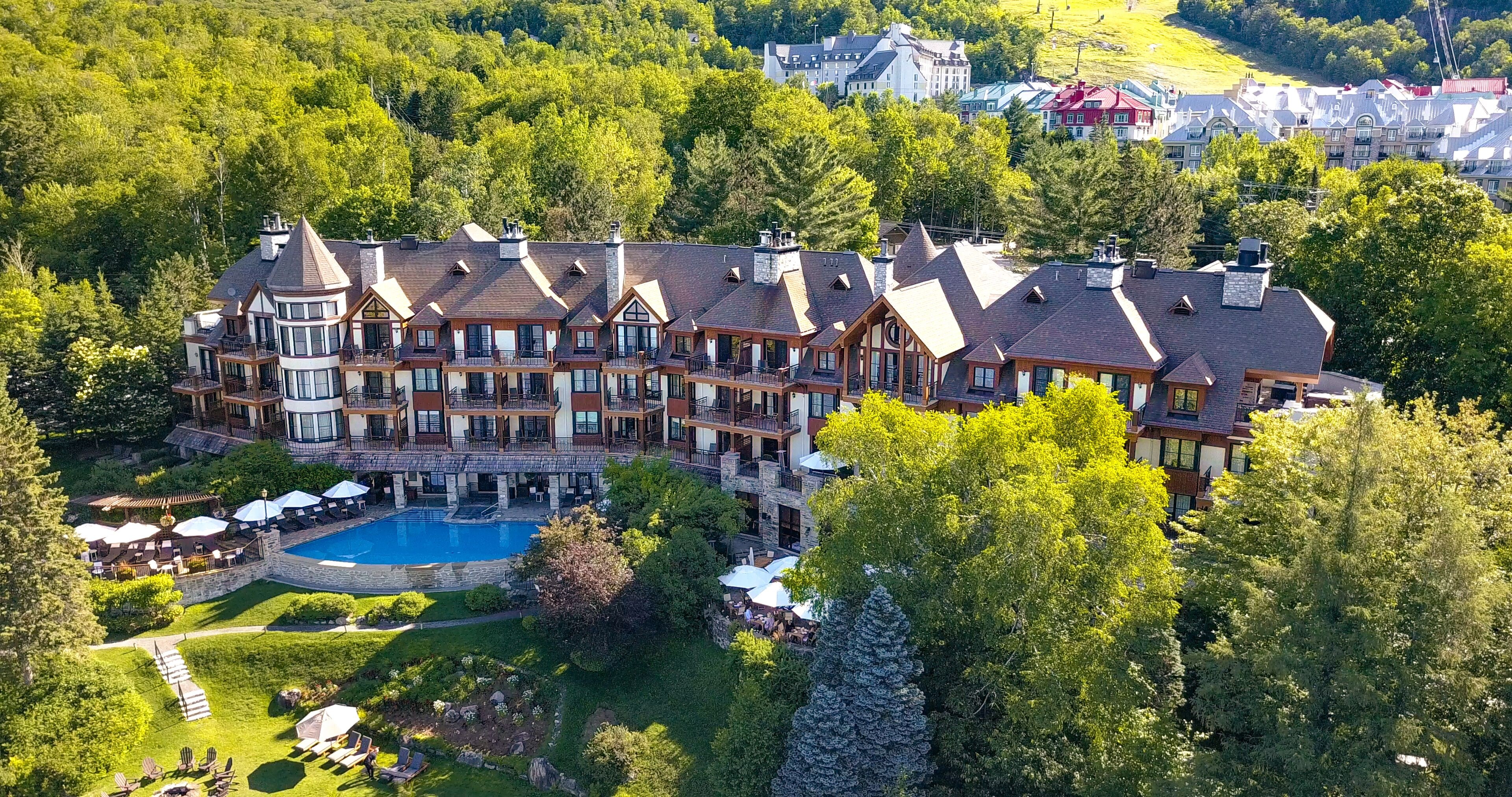 Um hotel grande, com vários andares, piscina e áreas de estar ao ar livre.