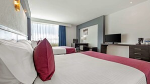 Quarto de hotel com uma cama grande, uma escrivaninha, uma televisão e uma máquina de café.