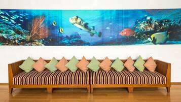 Um banco de madeira com almofadas listradas e um mural de peixes coloridos acima.
