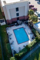 Vista aérea de um hotel com piscina, área de estar externa e estacionamento.