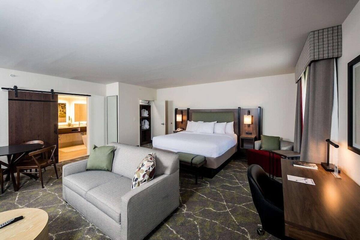 Quarto de hotel com uma cama, um sofá, uma escrivaninha e um espaço de refeições.