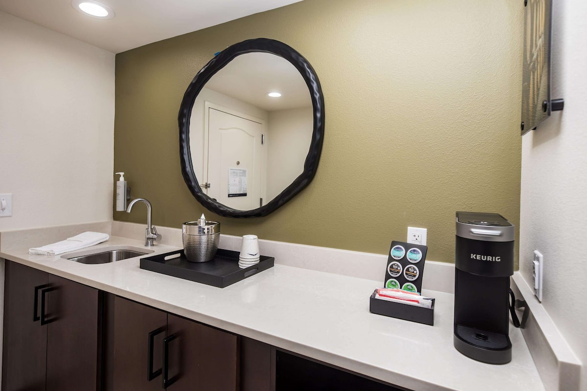 Casa de banho de hotel com lavatório, espelho e máquina de café Keurig.