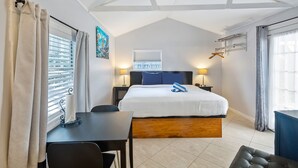 Quarto com cama, mesas de cabeceira, escrivaninha e uma cadeira.