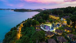Um resort com vários edifícios, piscina e vegetação exuberante.
