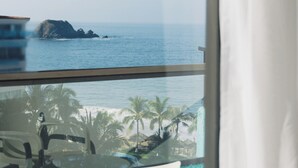 Vista de varanda com vista para o mar, com uma cadeira e uma mesa de vidro em primeiro plano.
