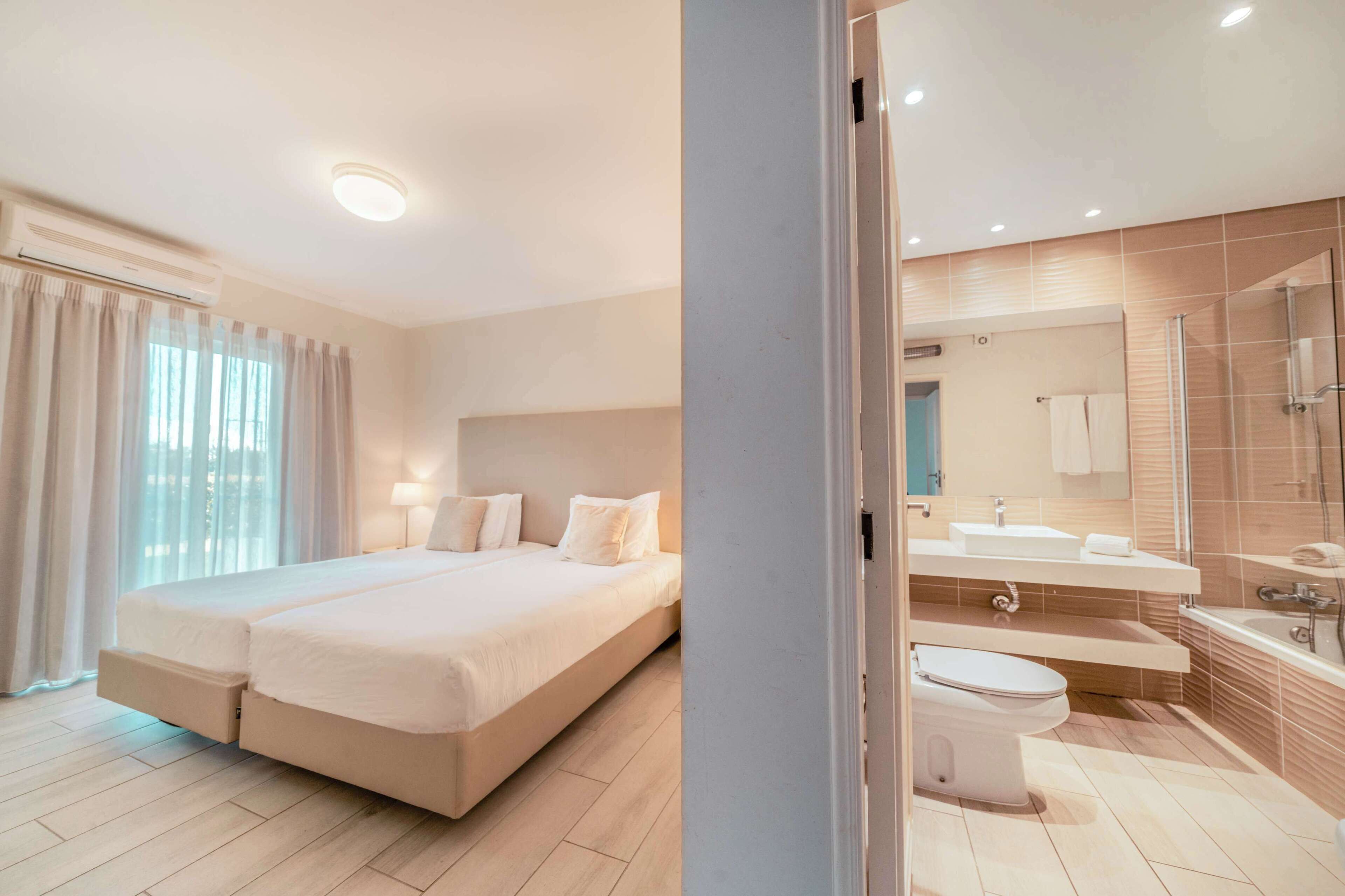 Quarto de hotel moderno com uma cama grande, banheiro com chuveiro e vaso sanitário.