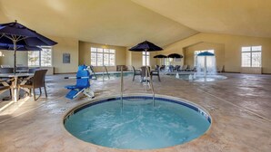 Uma área de piscina com espreguiçadeiras, guarda-sóis e uma banheira de hidromassagem.