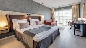 Quarto de hotel moderno com uma cama grande, uma escrivaninha e um sofá.