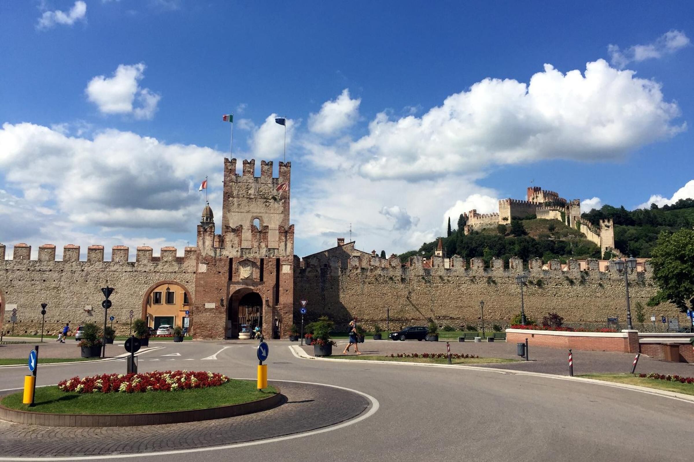 Um castelo de pedra histórico com uma torre imponente e uma muralha fortificada.