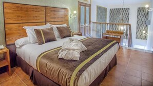 Quarto de hotel com uma cama grande, cabeceira de madeira, varanda com guarda-corpo de madeira e cortinas estampadas.