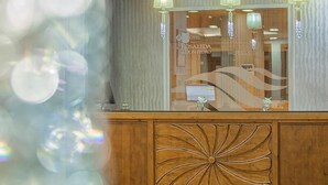 Uma mesa de recepção com design em painel de madeira, divisória de vidro e placa com a inscrição 'Hotel Rosaleda Don Pedro'.