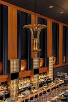 Uma área de bar com um balcão extenso, diversas opções de assento e um lustre decorativo.