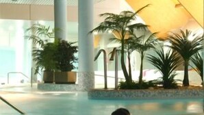 Um homem relaxando em área de piscina com palmeiras e design arquitetônico moderno.