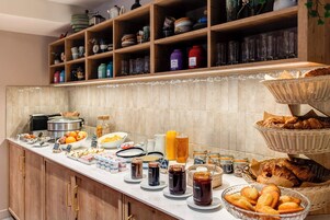 Um buffet de café da manhã com diversos alimentos, acompanhamentos e seleção de bebidas.