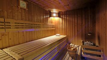 Uma sauna de madeira com bancos e um banco de madeira, um balde e uma escova.