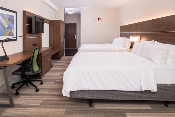 Quarto de hotel com uma mesa, duas camas, televisão e porta que dá para outro aposento.