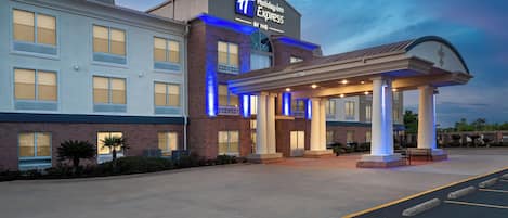 Um hotel Holiday Inn Express com entrada coberta, estacionamento e céu limpo.