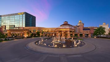Um hotel com fachada de vidro moderna, um pátio central com uma fonte e um edifício tradicional com cúpula.
