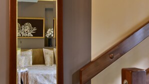 Um quarto com uma cama, almofadas, mesa de cabeceira e uma obra de arte emoldurada na parede.