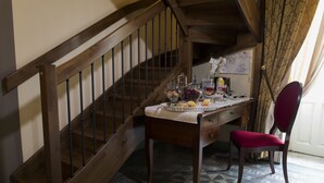 Uma escadaria com guarda-corpos de madeira, uma mesa de jantar com uma cadeira vermelha e um piso estampado.