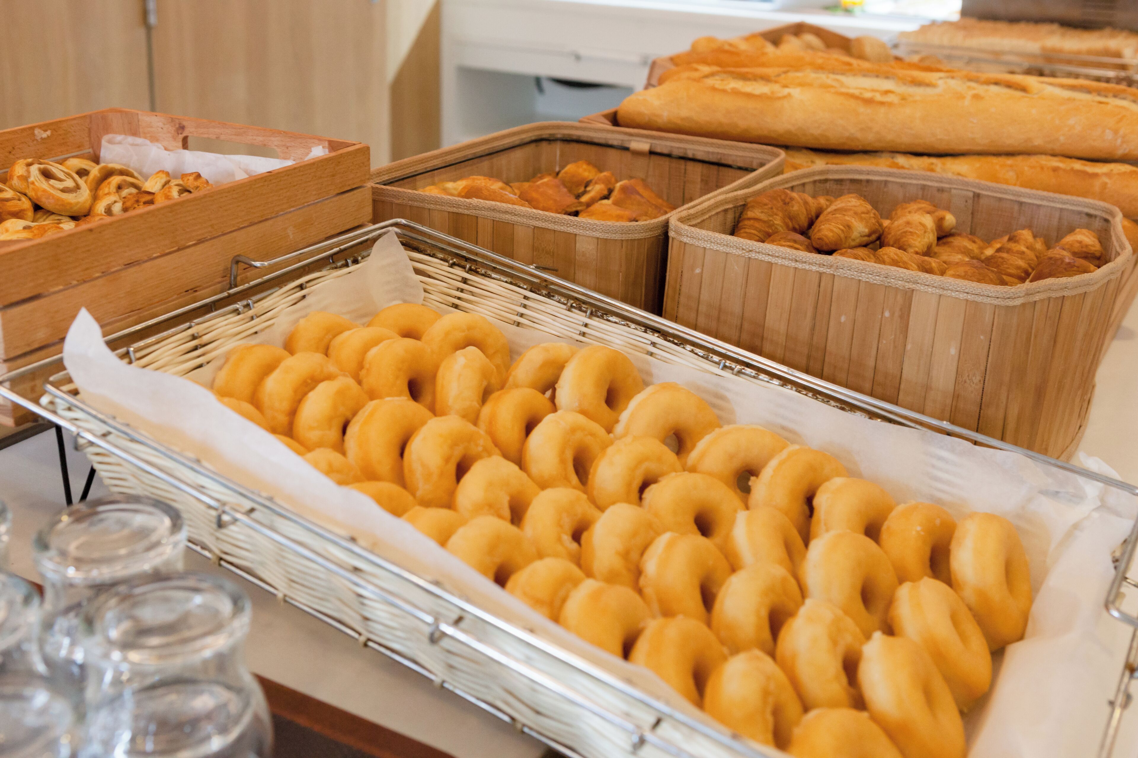 Buffet com diversos produtos de panificação, incluindo donuts e doces.