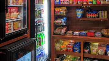 Uma área com lanches e bebidas, com vitrines refrigeradas e prateleiras repletas de diversas opções.