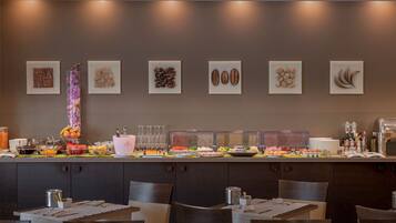 Uma área de buffet com diversas opções de comida e uma seleção de obras de arte emolduradas na parede.