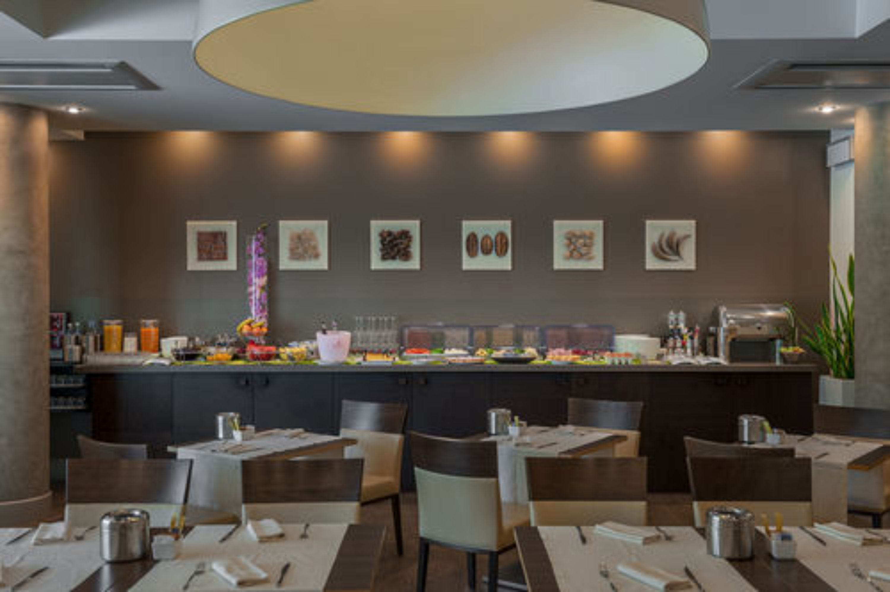 Restaurante moderno com área de bar central, diversas mesas e cadeiras.
