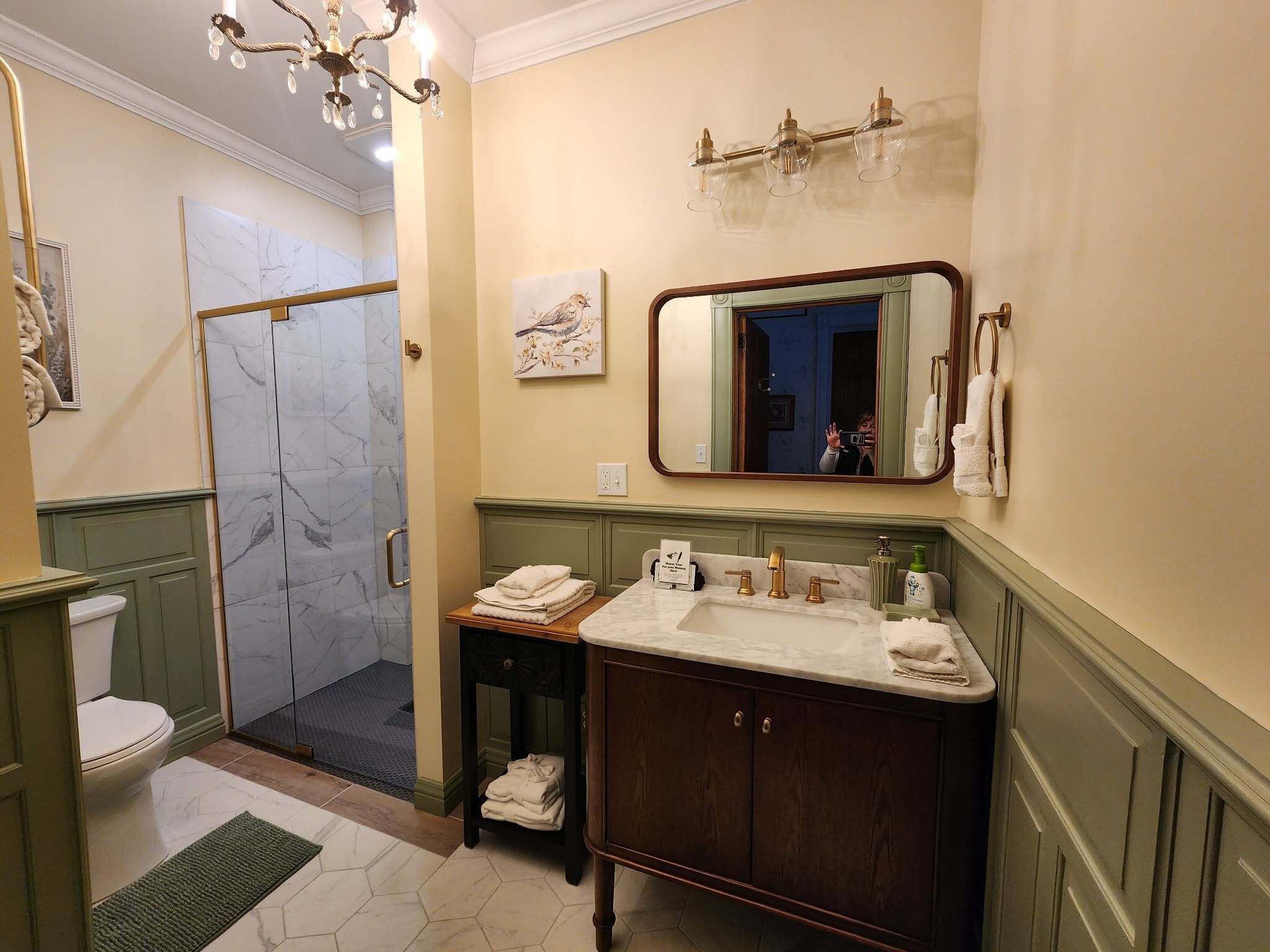 Casa de banho com chuveiro de mármore, toucador com espelho e porta-toalhas.