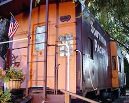 Um vagão-trem antigo da Southern Pacific, com uma bandeira, janelas e porta.