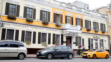 Hotel com fachada amarela, várias janelas com persianas e uma placa indicando uma cozinha.