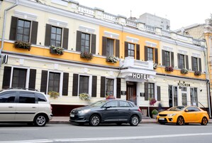 Hotel com fachada amarela, várias janelas com persianas e uma placa indicando uma cozinha.