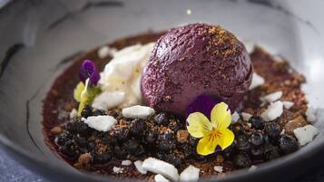 Sobremesa com uma bola de sorvete e frutas vermelhas em um prato.