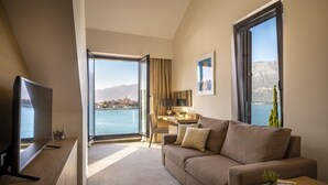 Quarto de hotel moderno com uma janela ampla que oferece uma vista panorâmica do mar e das montanhas.