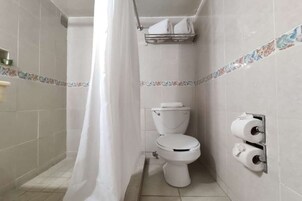 Uma casa de banho pequena e funcional com sanita, cortina de chuveiro e rolo de papel higiénico.