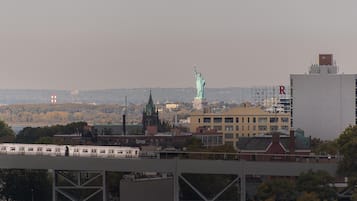 Paisagem urbana com uma estátua imponente, um trem e diversos edifícios.