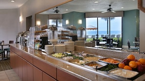 Buffet com diversos alimentos e vista para o oceano.