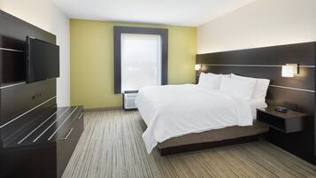 Quarto de hotel com cama, mesas de cabeceira, televisão de tela plana, janela e luminária fixada na parede.